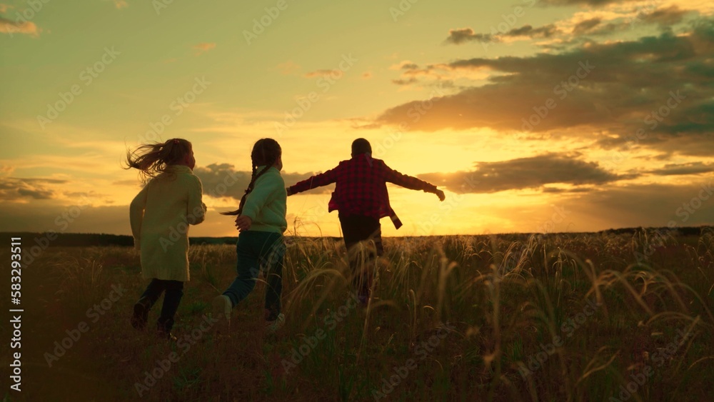 Foto Stock Children run together in park at sunset on grass. Happy ...
