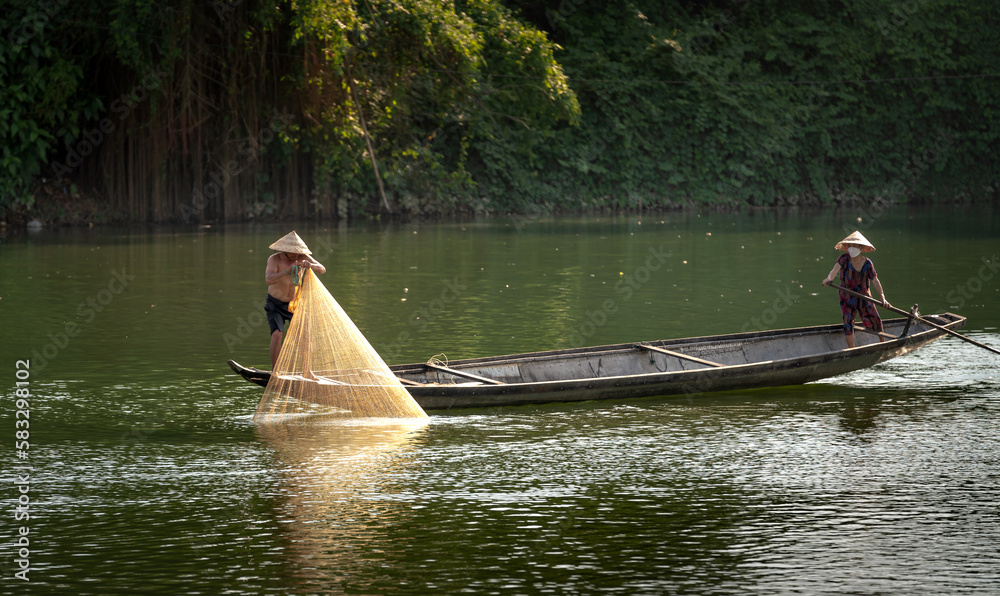 Vietnamese fishermen catching fish and throwing out two large yellow ...