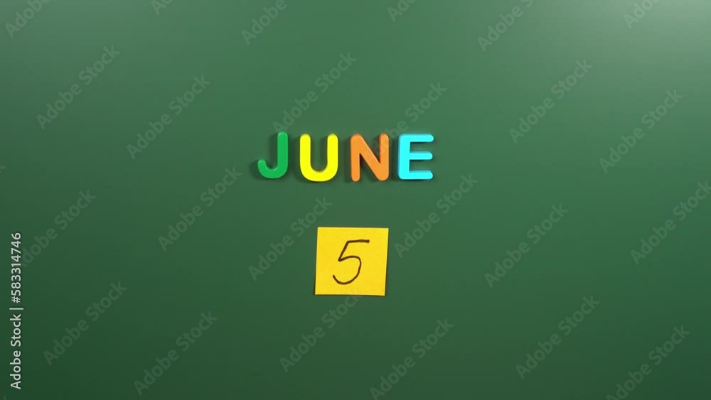 Hand sticking a sticker 5 June calendar day on school board. 5 date of ...