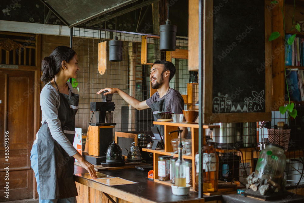 the female barista talking to the male barista that standing inside the ...