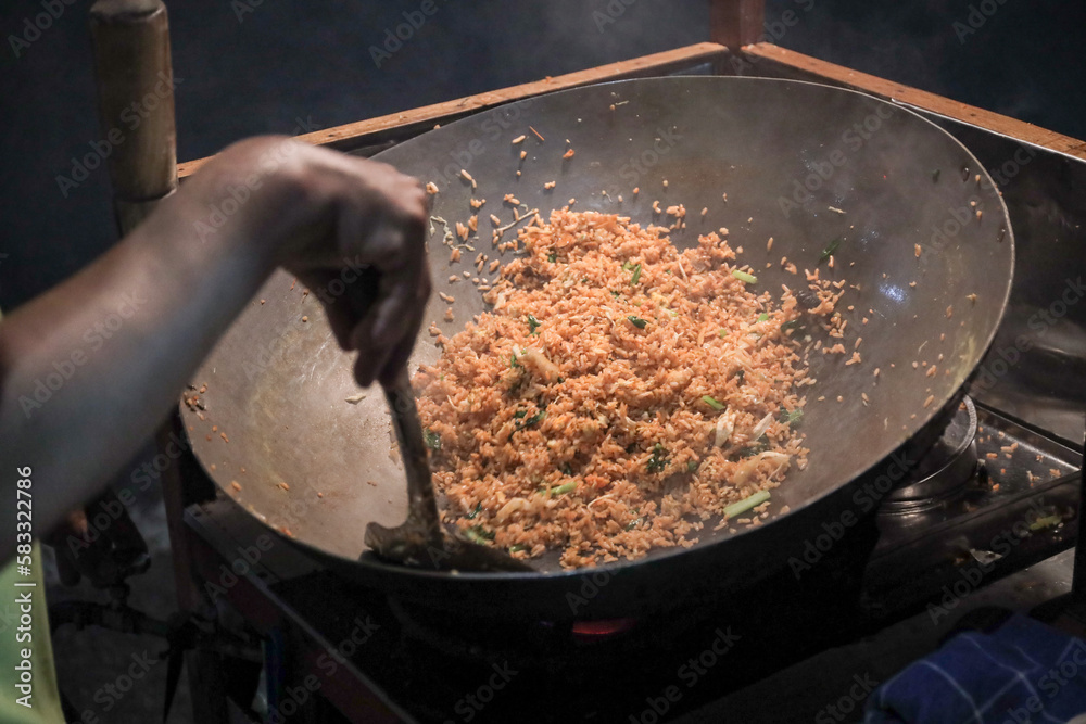 A man cooking fried rice on steel skillet pan for selling on the street ...