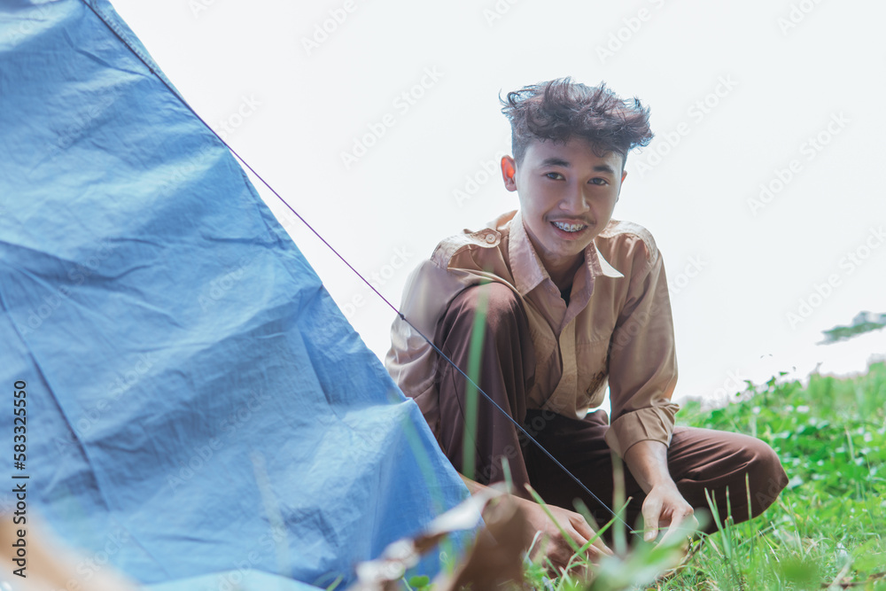a teenage boy wearing scout clothes smiles at the camera while ...