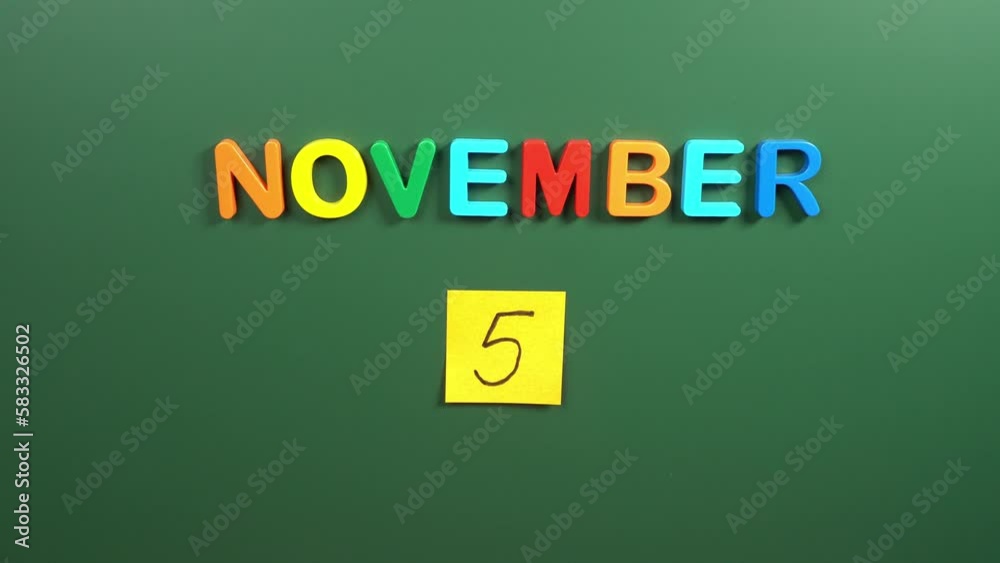 Hand sticking a sticker 5 November calendar day on school board. 5 date ...