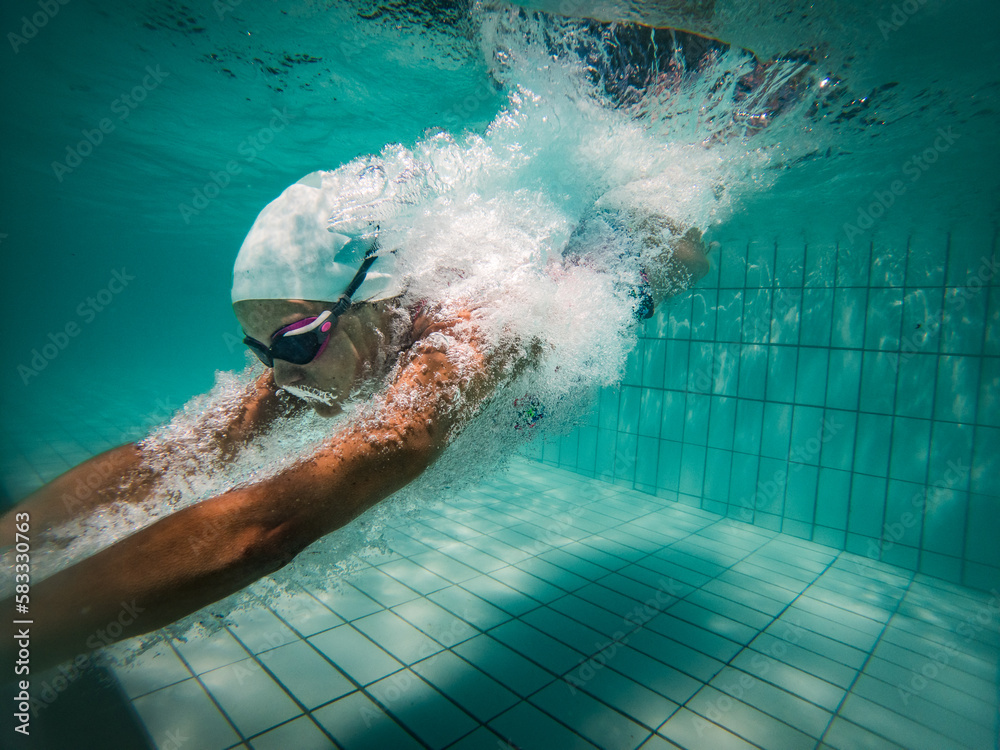A talented female swimmer dives into a full-size tournament pool to ...