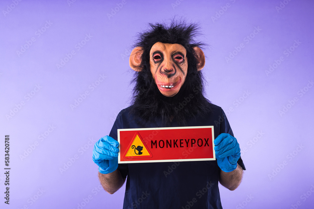 Disguised person with a monkey mask and a doctor's suit, holding a sign ...