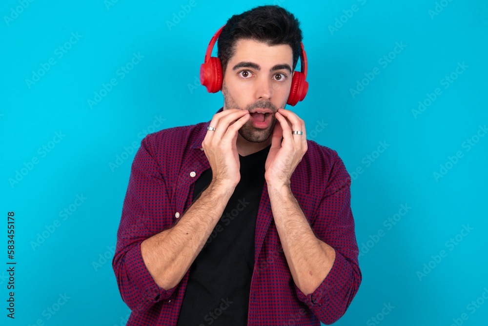 Shocked Young man standing over blue studio background stares fearful ...