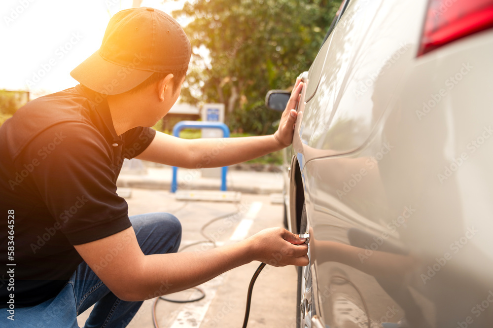Asian man inflating tires at gas station And he's looking at the dial ...