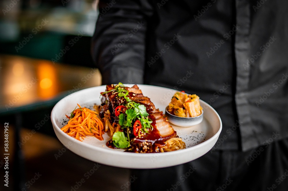 chef hand hold plate whith Stewed pork slice with noodles and ...