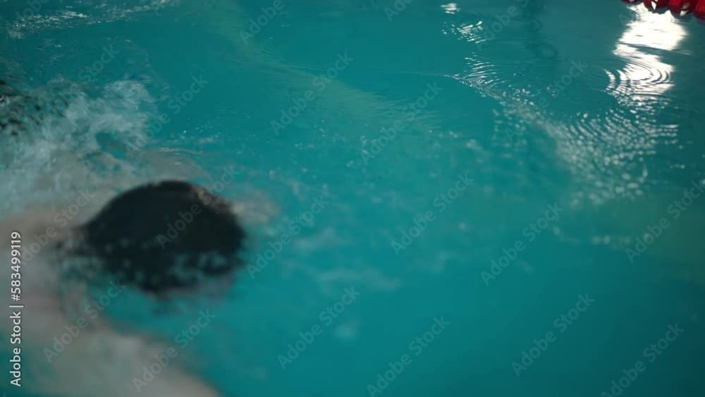 Blue water splashing on poolside as young swimmer swimming in slow ...