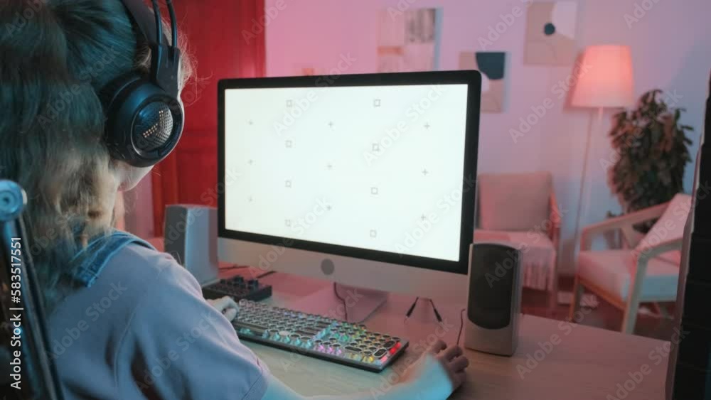 Back view of gen z gamer girl in gaming headphones playing game on PC ...