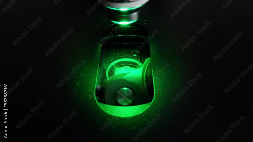 Moving the corrective lens focusing the green light of the microscope ...