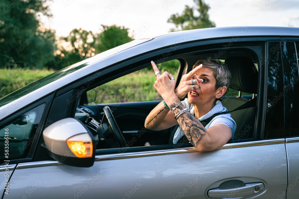 woman senior mature driver show middle finger trough the window of car ...