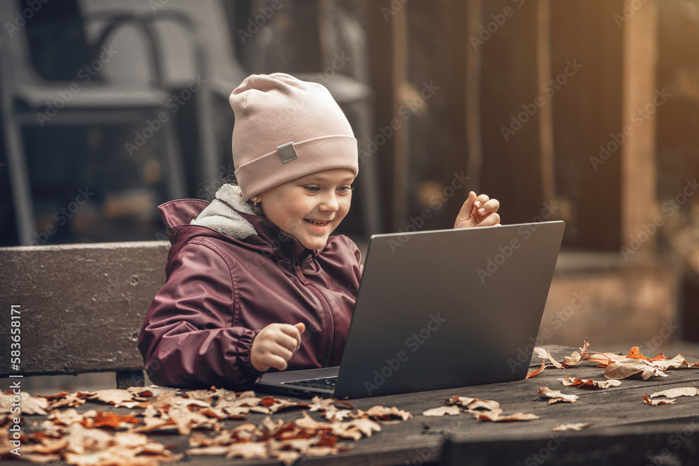 Cute little girl using a laptop computer for online learning at an old ...