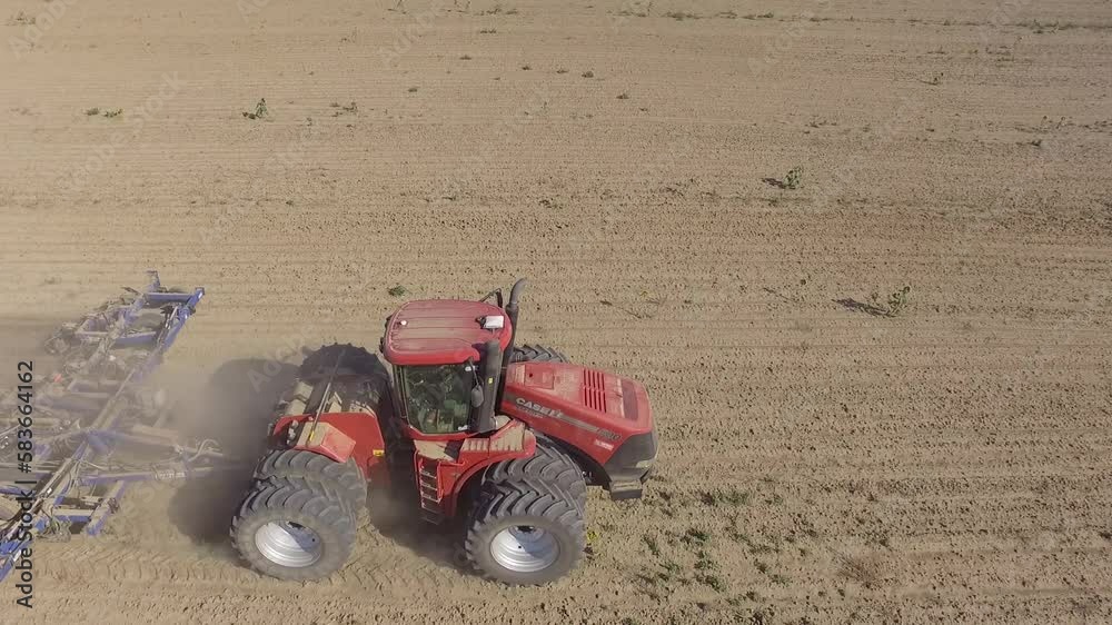 Big red tractor working on the field cultivating and applying nitrogen ...