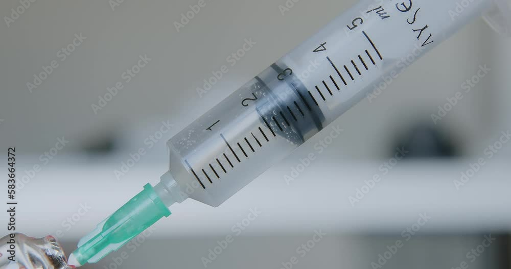 The doctor dials an antibiotic from a glass ampoule into the syringe ...