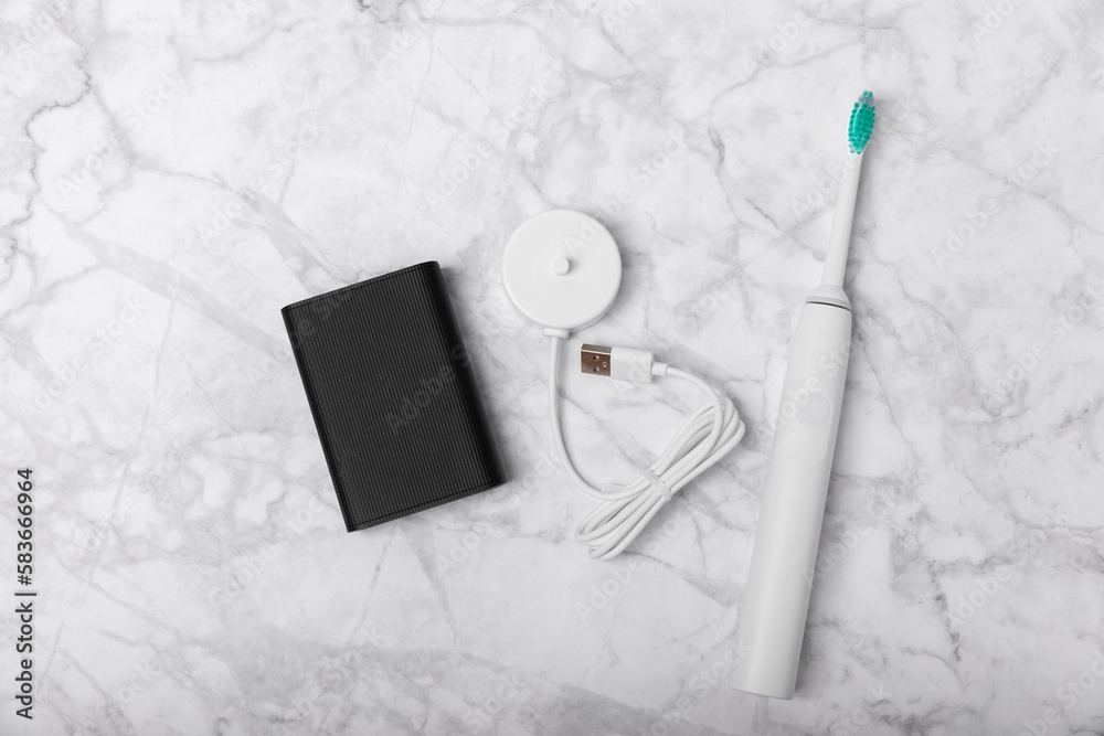 A modern electric toothbrush is charged from an external power bank ...