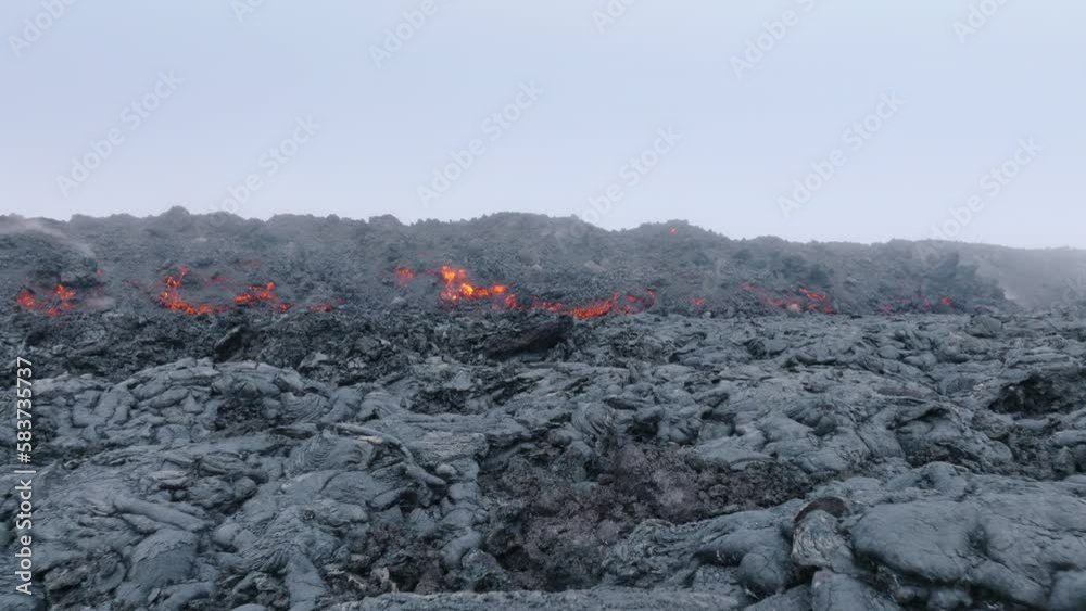 Drone flying to steaming black lava rocks. Red hot molten lava flowing ...