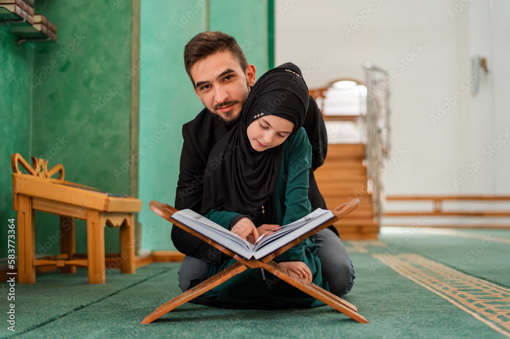 A happy Muslim family young father with child daughter reading a holy ...
