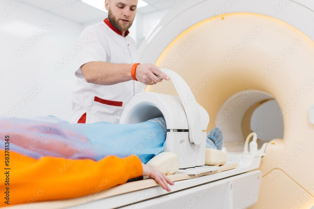 Woman doctor makes knee-joint MRI scanning. Young patient on automatic ...