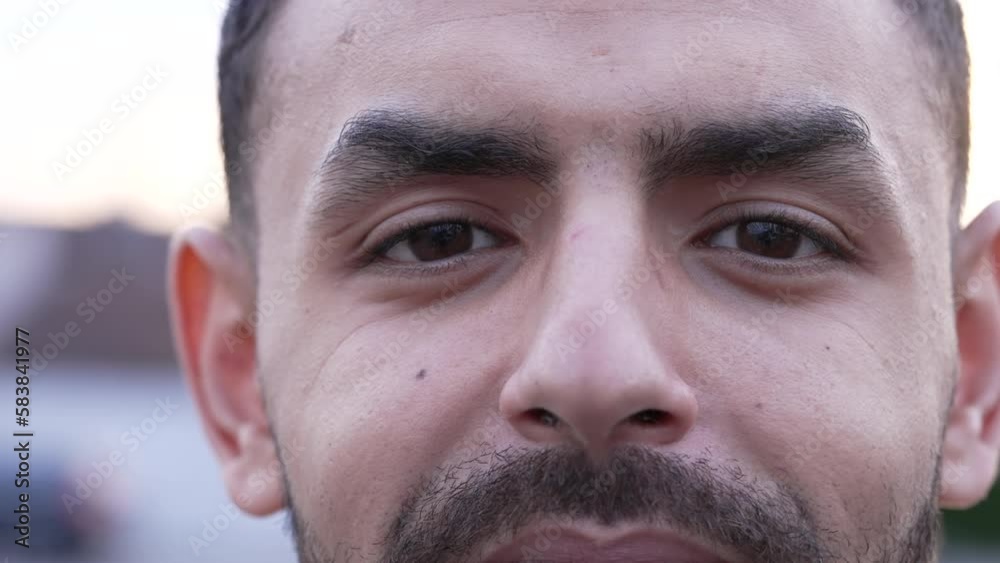 One Middle Eastern young man close up face and eyes smiling at camera ...