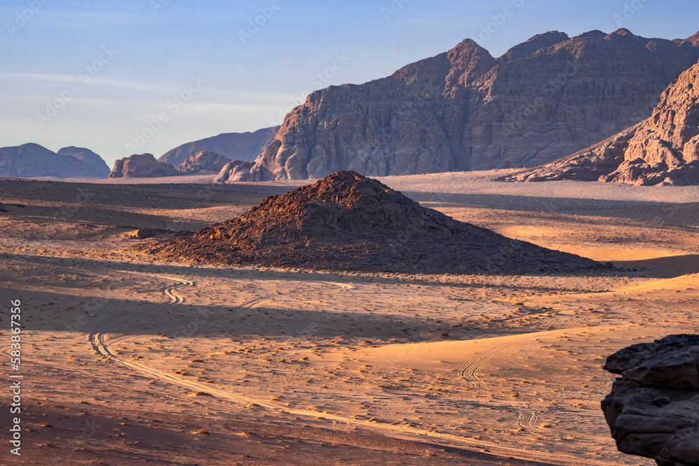 Wadi Rum plain at sunrise with soft light over the sand dunes and ...