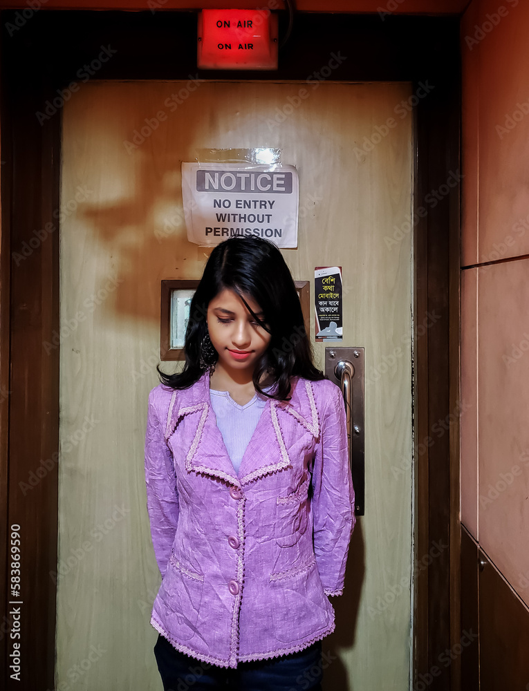 A female Rj ( Radio Jockey) Standing before On Air room with a No entry ...