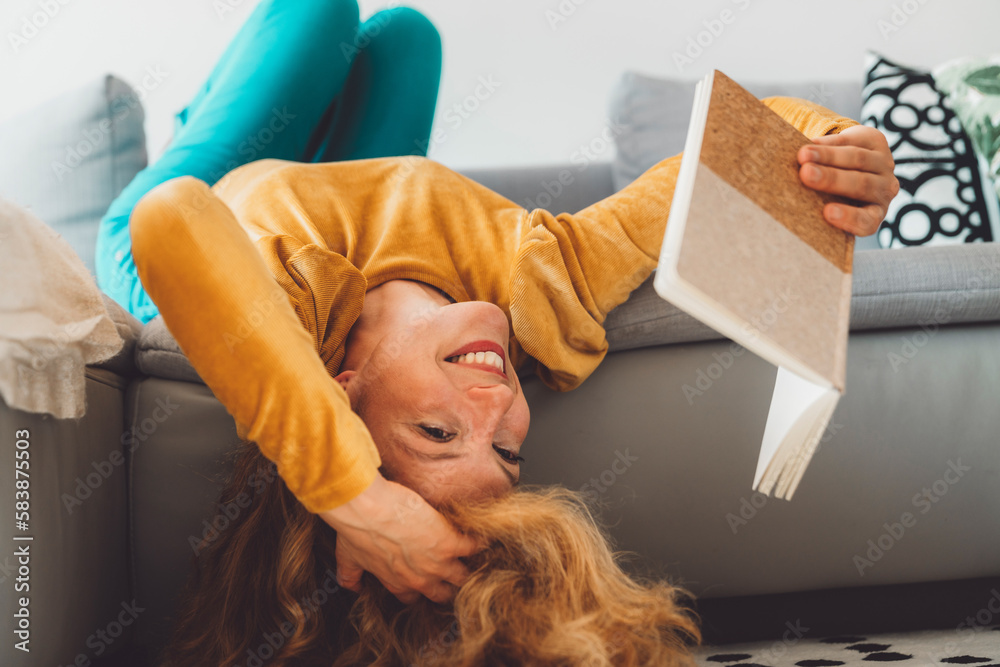 Trying to read upside down - Playful blonde curly woman reading a book ...