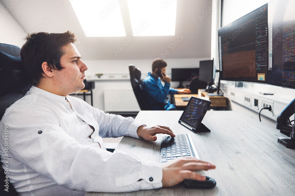 Side view waist up of two IT programmers coding in a bright office with ...