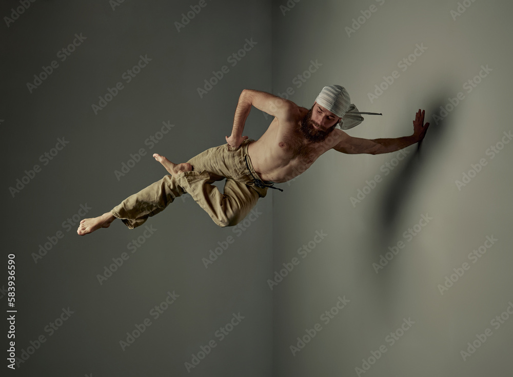 Bearded young man with strong muscular shirtless body training, doing ...
