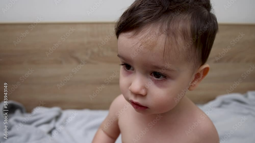 Vidéo Stock crying baby lying on bed rubbing eyes with hands.angry ...