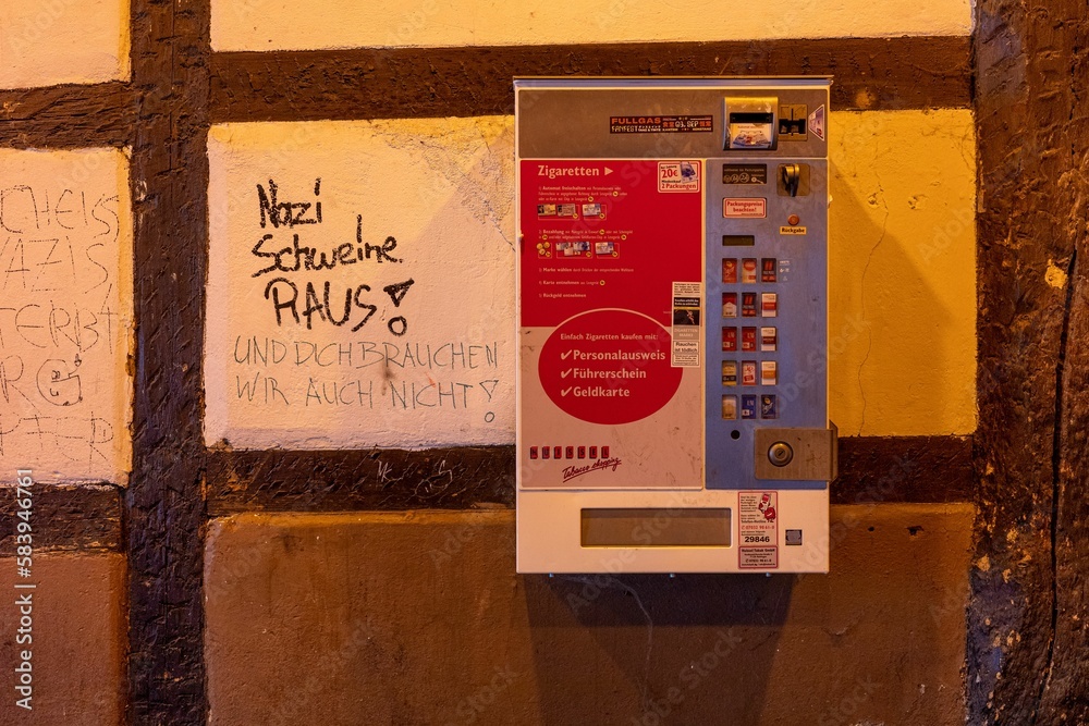 Cigarette vending machine on a weathered grungy wall with graffiti and ...