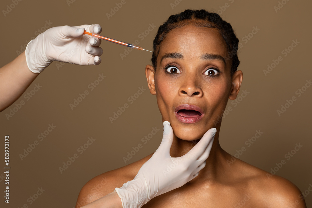 Shocked black middle aged woman receiving beauty shots, using injection ...