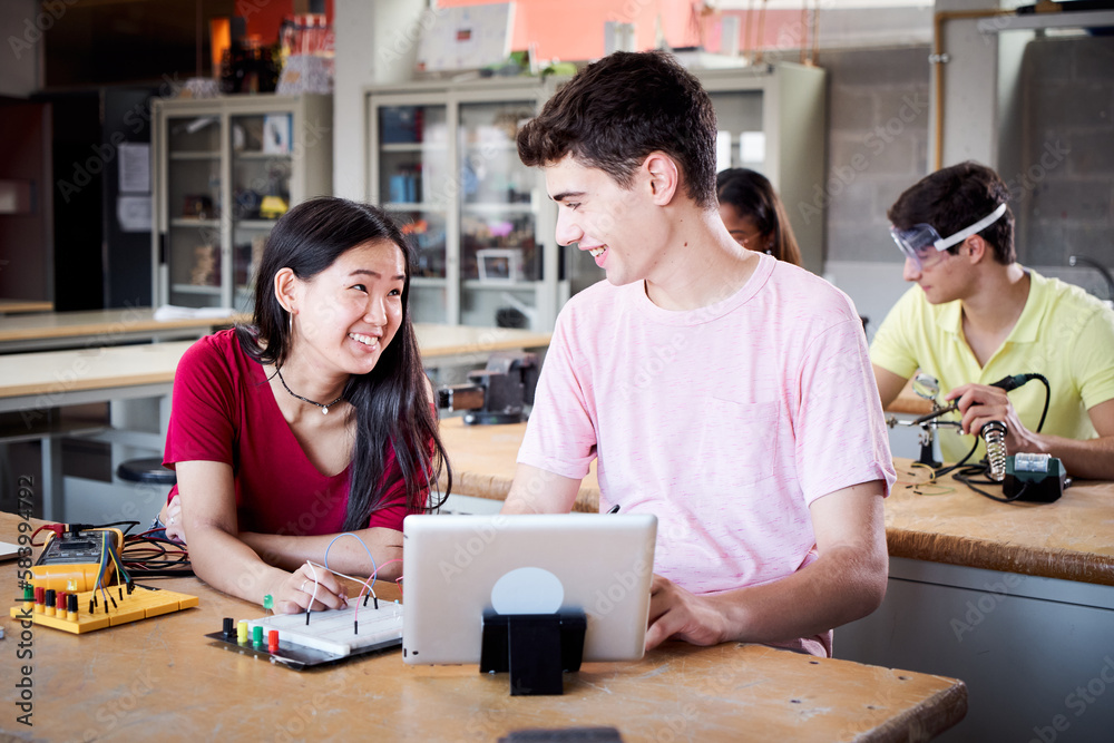 Multiracial boy and girl students at a technical high school look at ...