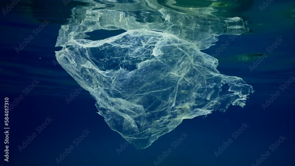 Close-up of plastic bag scraps floating in blue water, Slow motion ...