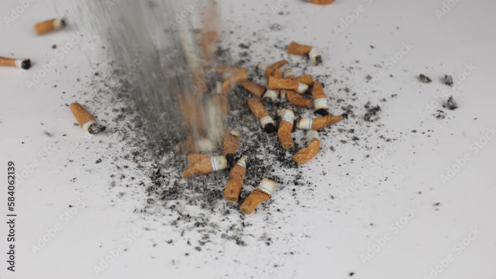 Cigarettes and ashes, many smoked cigarettes scattered on a white cloth ...