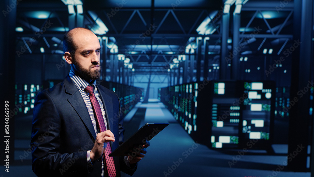 IT engineer using tablet in high tech server room, planning networking computer system. Database ...