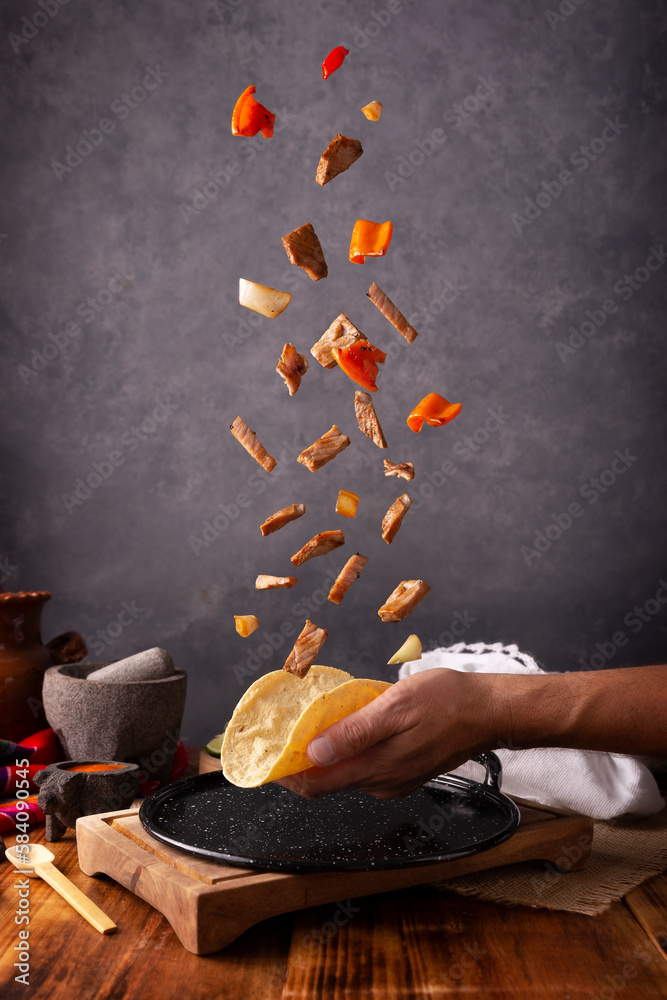 Exploding Beef Fajita Taco ingredients falling on human hand with corn ...