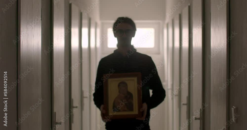 Portrait of young man with icon Blessed Mother Mary and Jesus child of ...