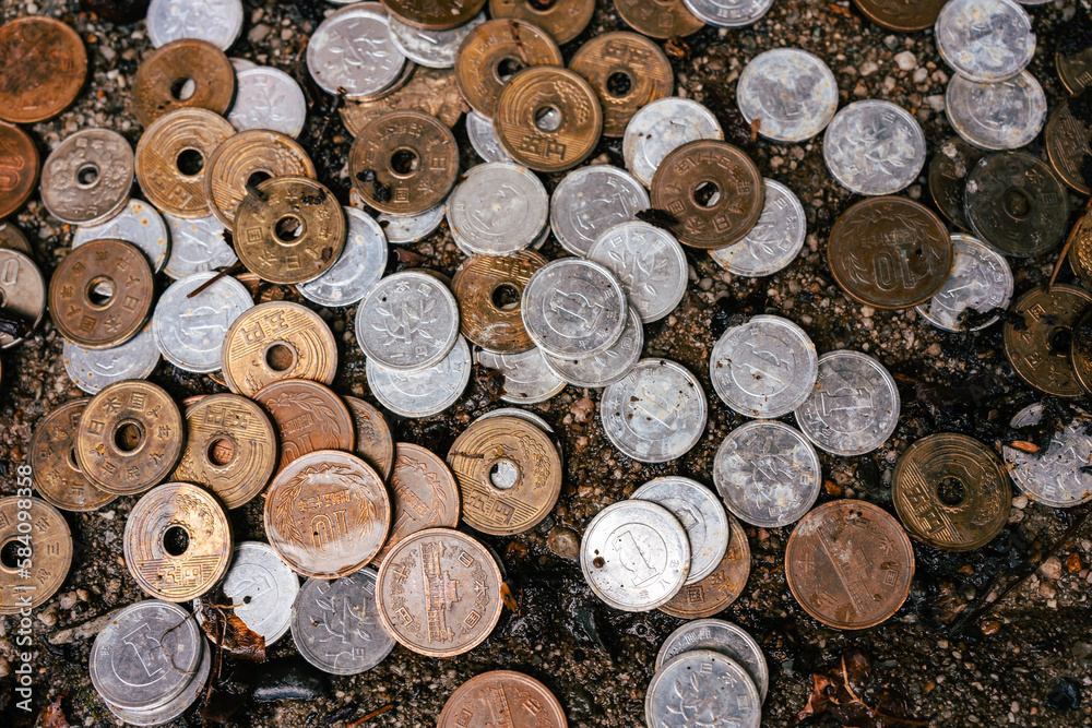 Japanese coins lie as an offering on the damp wall of a shrine. Silver ...
