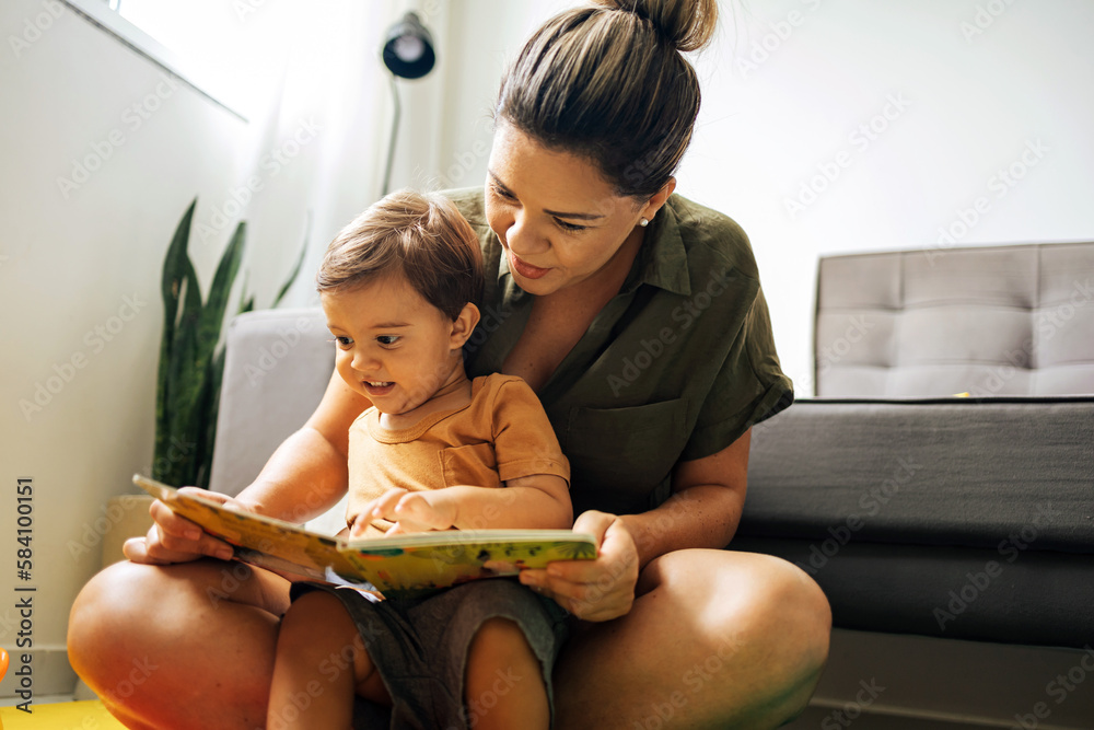 Mom reading a book with baby boy at home. Early age children education ...