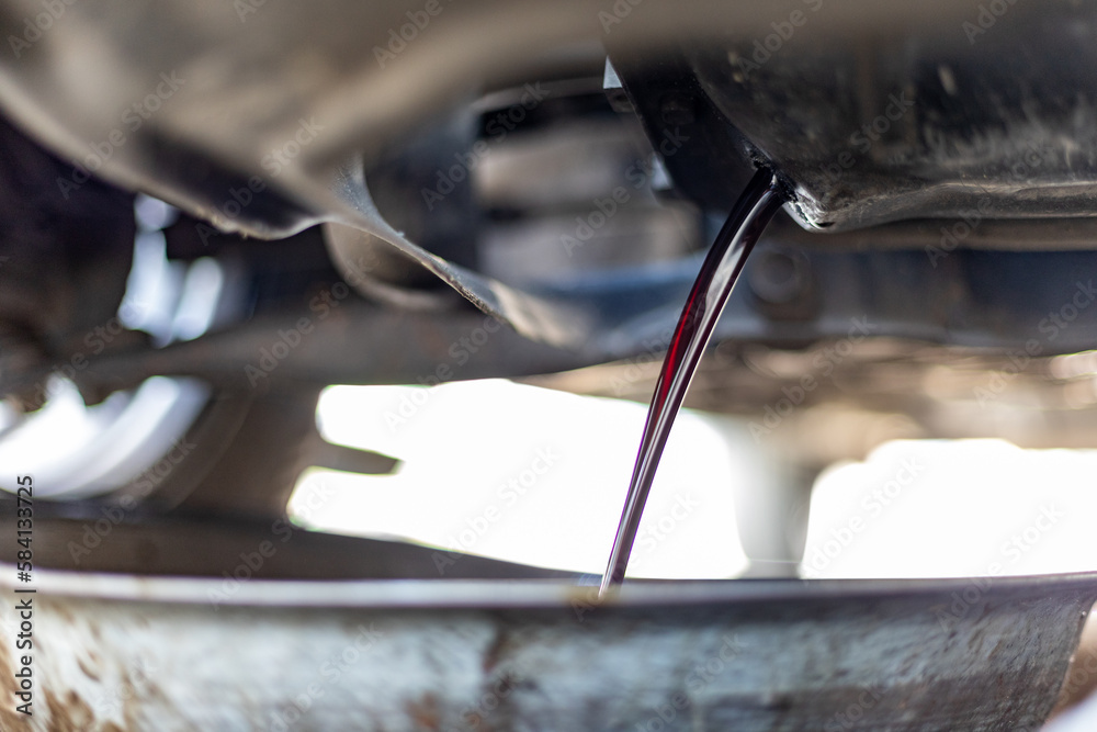Changing engine dirty oil being drained from underneath a car into a ...