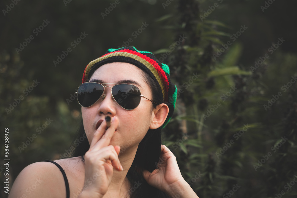 Yong Asia woman smoking marijuana at cannabis tree plant background Stock-Foto | Adobe Stock