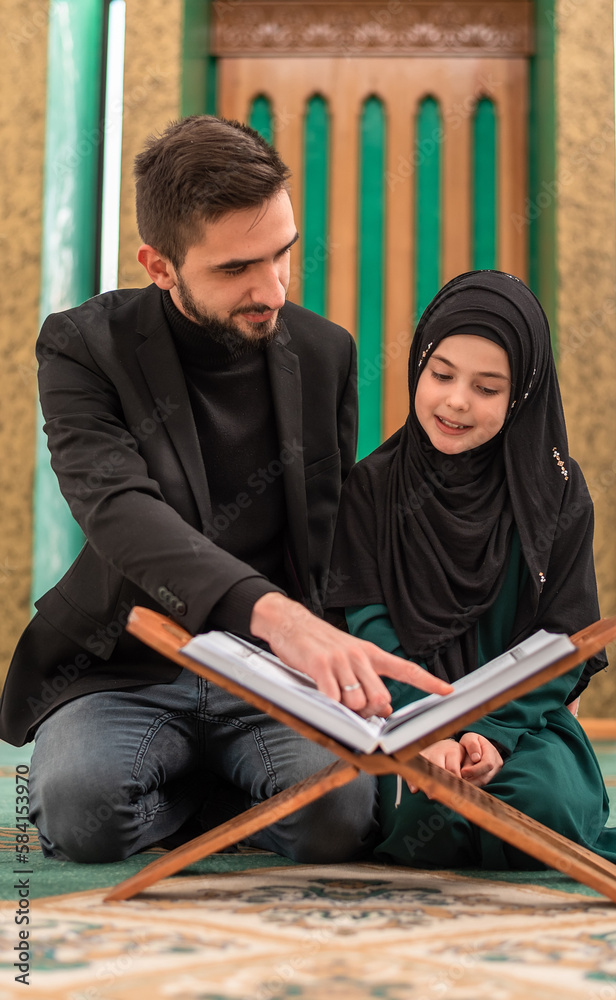 A happy Muslim family young father with child daughter reading a holy ...