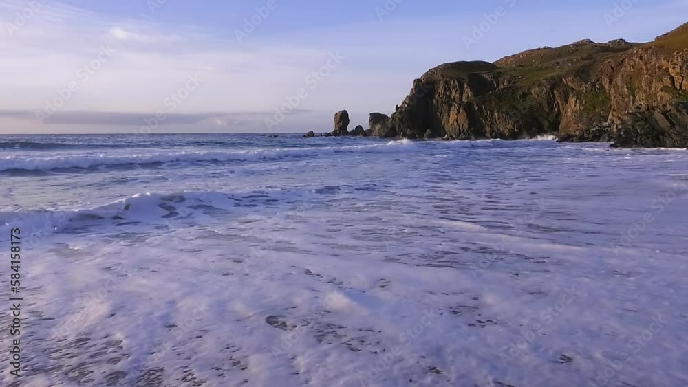 Golden hour shot of some waves, the beach and the headland around ...