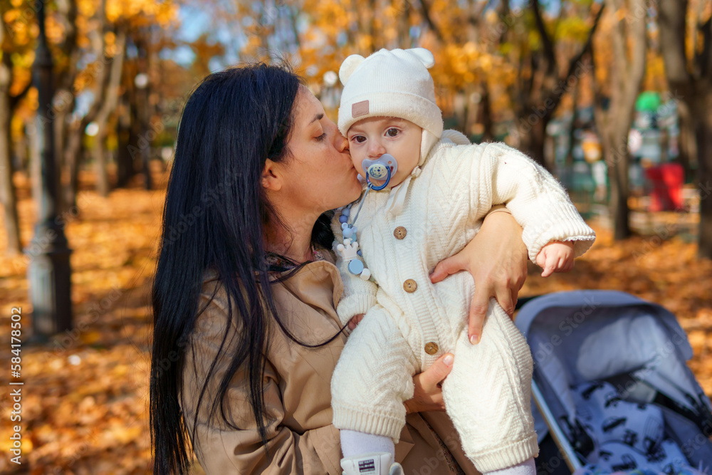 mother and baby are in autumn city park, happy people walking together ...