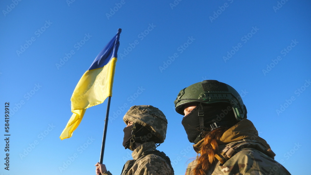 Young soldiers of ukrainian army standing at peak of hill with raised ...