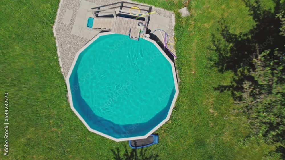 Drone footage looking down at a small pool on a sunny day. Camera moves ...