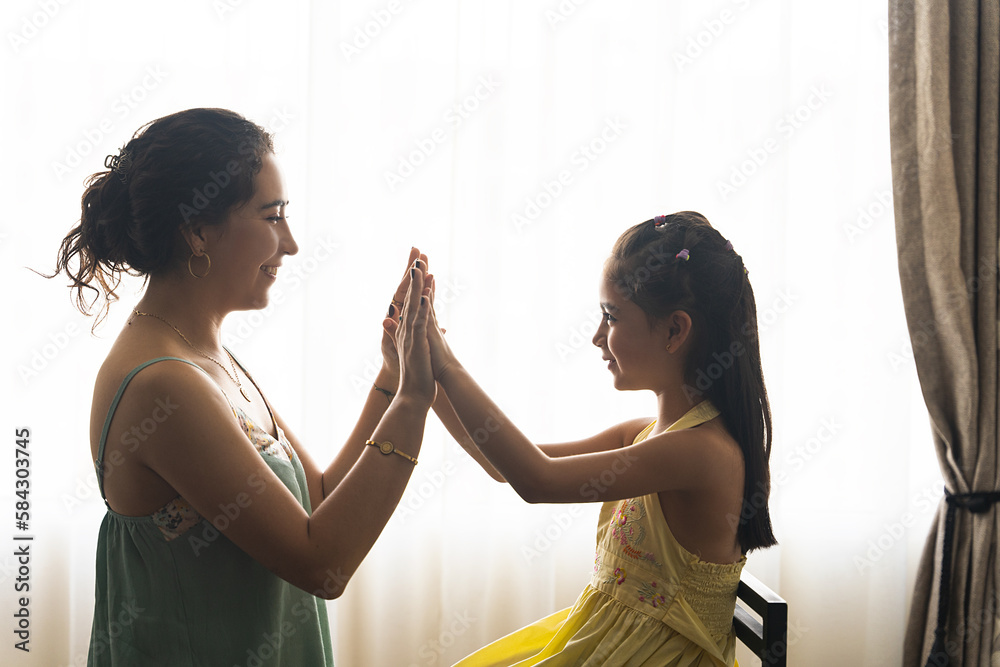Mother and daughter engaging in a playful clapping game, enjoying a ...