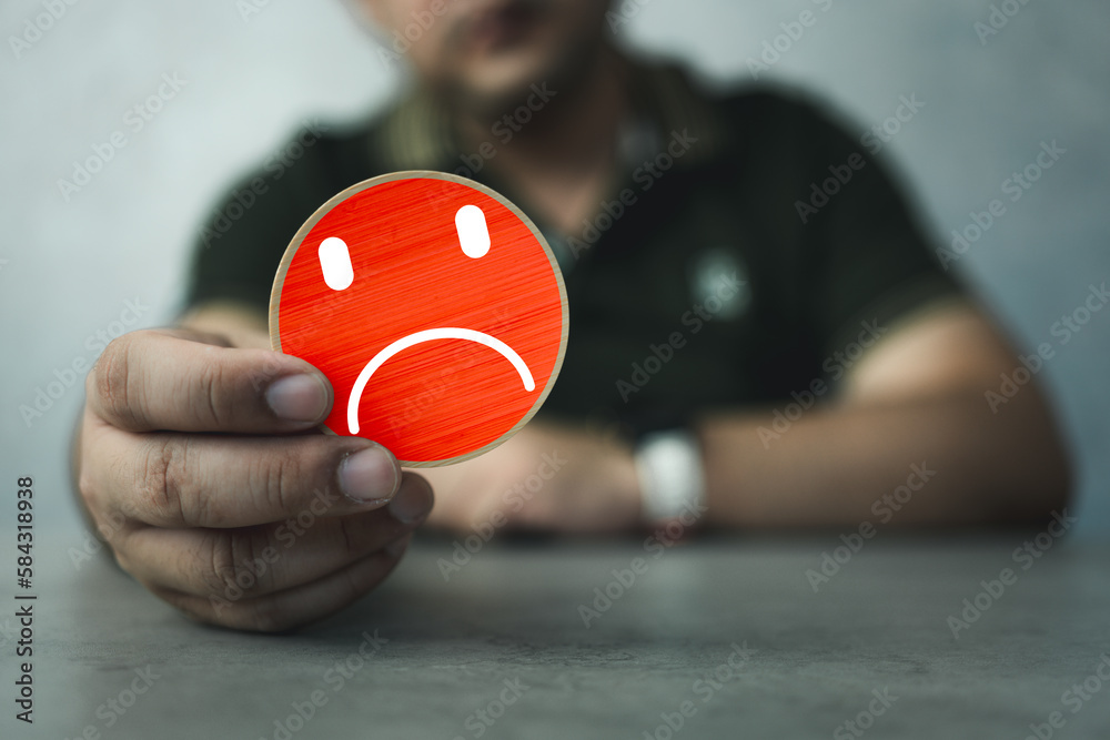 Hand holds wood circle with an unhappy angry face. Customer review, bad ...