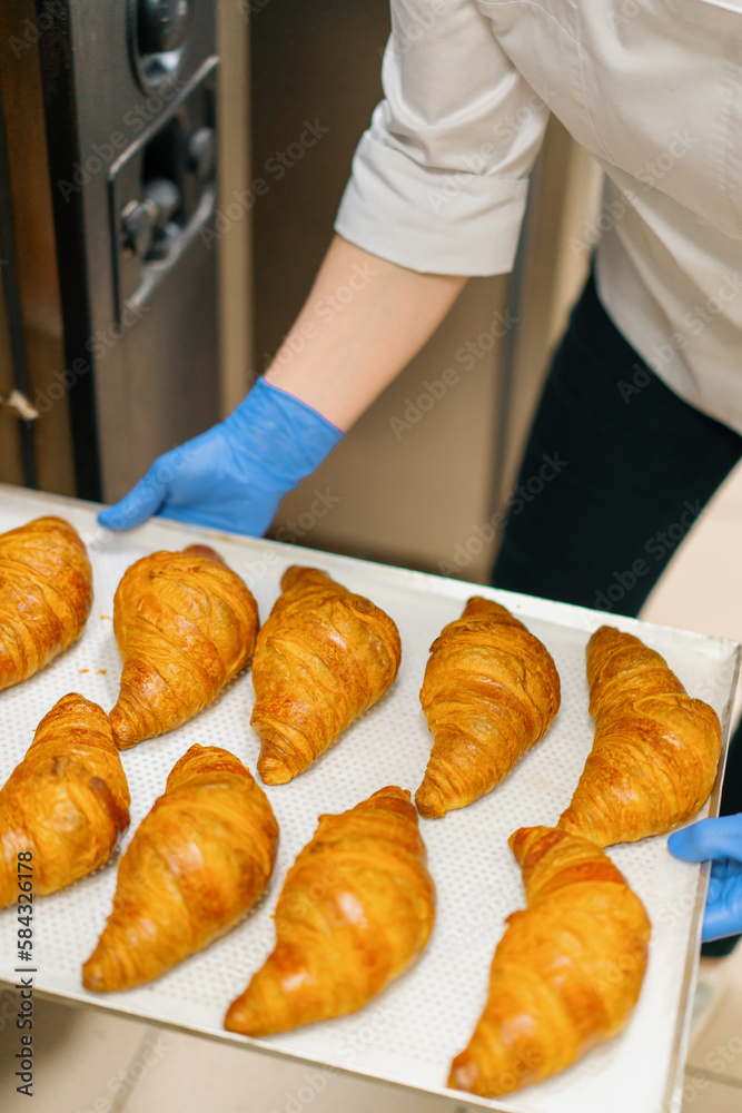 Foto de Kitchen in the bakery - ready-made croissants are taken from ...